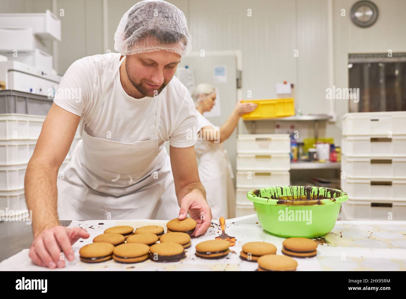 Baker apprentice baking and decorating double biscuits with chocolate ...