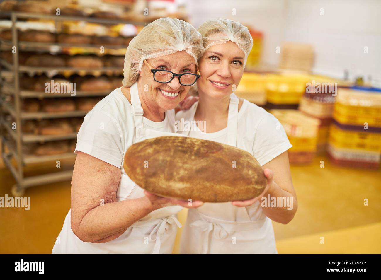Two women from the bakery team proudly show off the finished loaf of ...