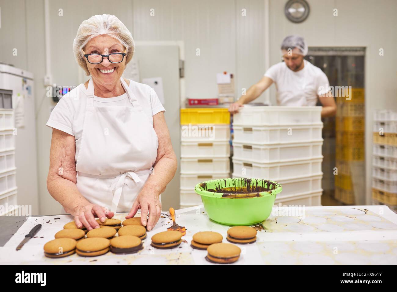 Senior baker decorates double biscuits with chocolate in the family ...