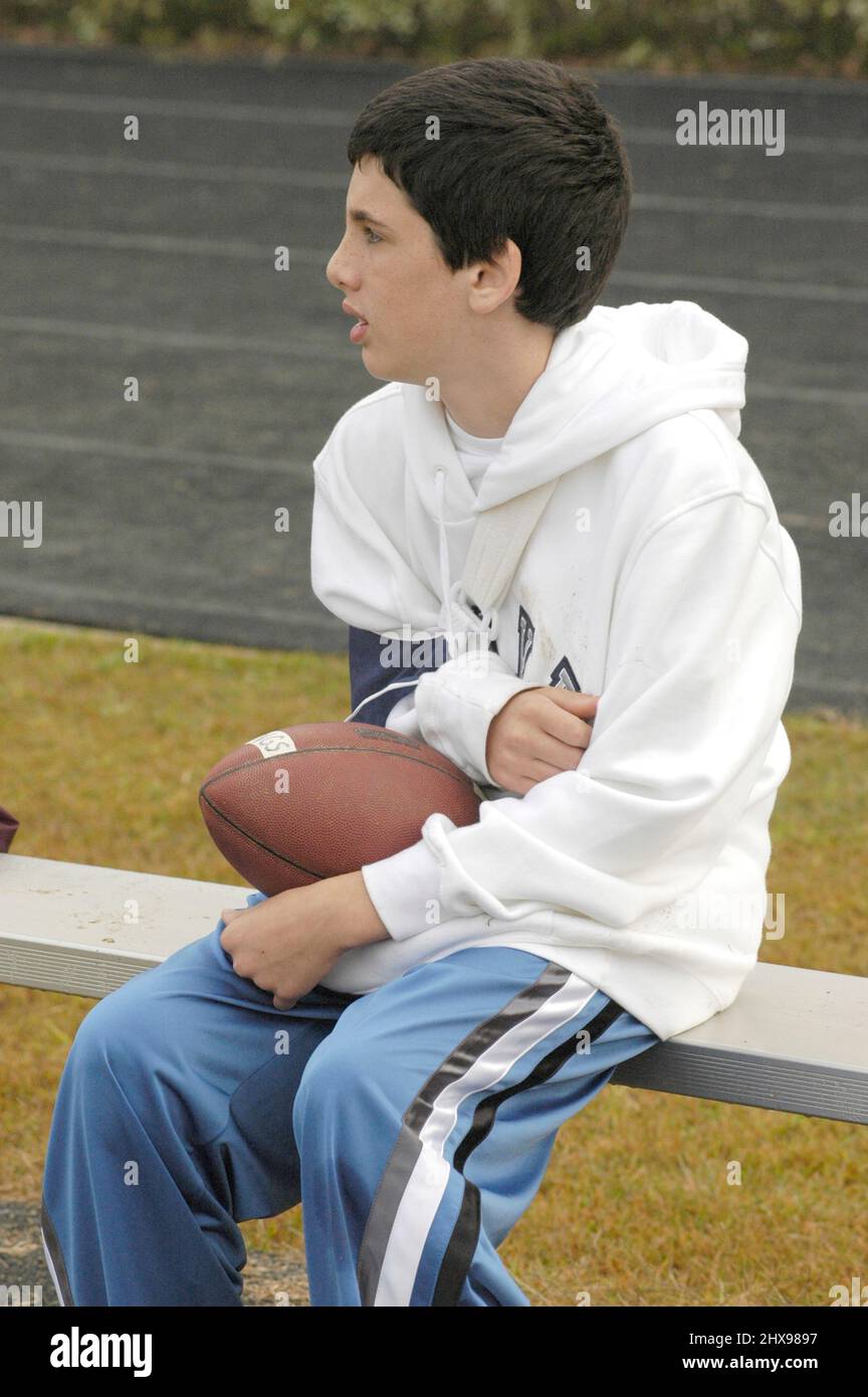 Injured young football player on bench with arm in cast from injurie ...