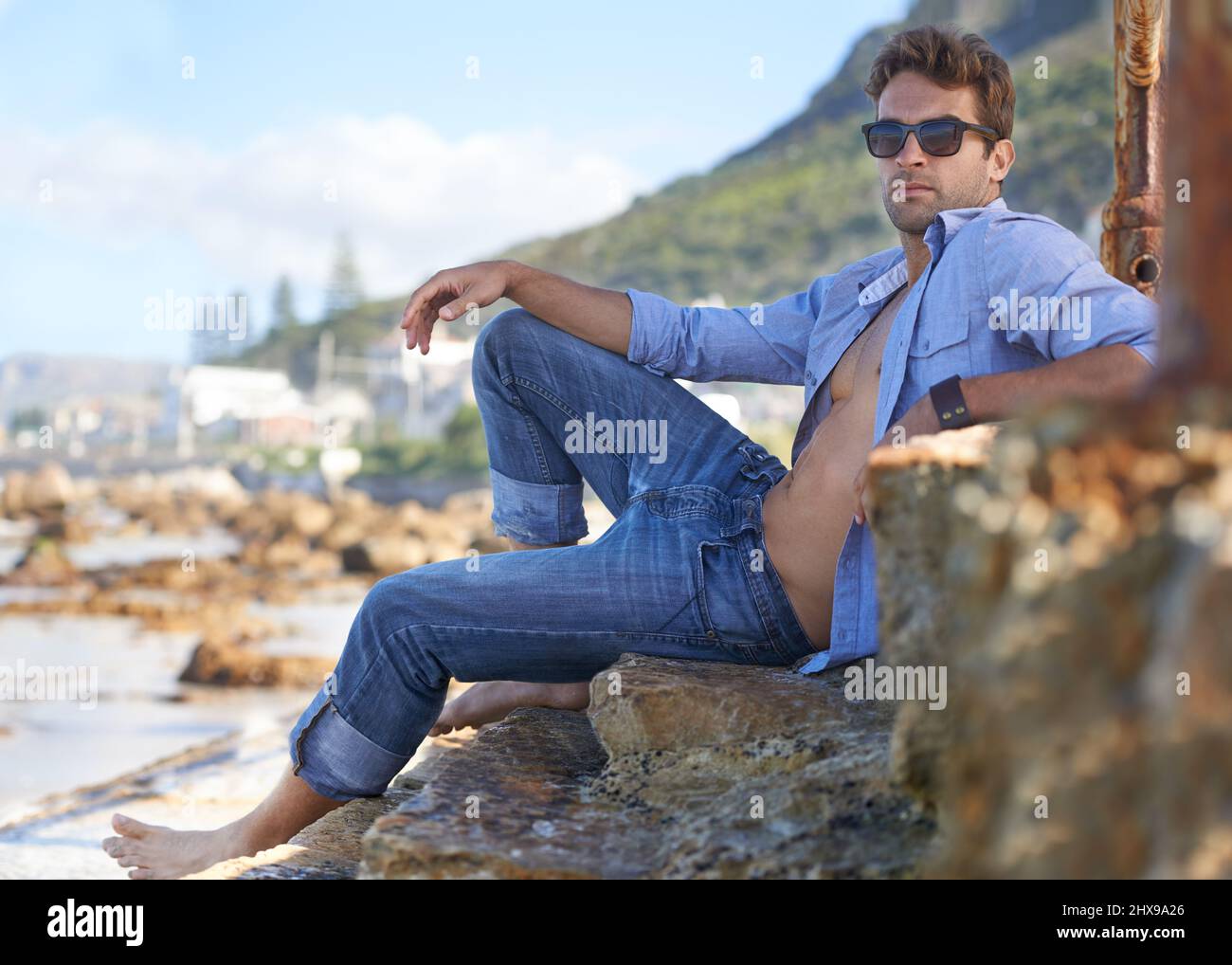 Taking in the scenery. A young man relaxing at the beach Stock Photo ...