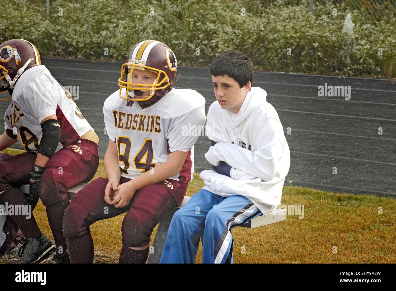 Injured young football player on bench with arm in cast from injurie ...