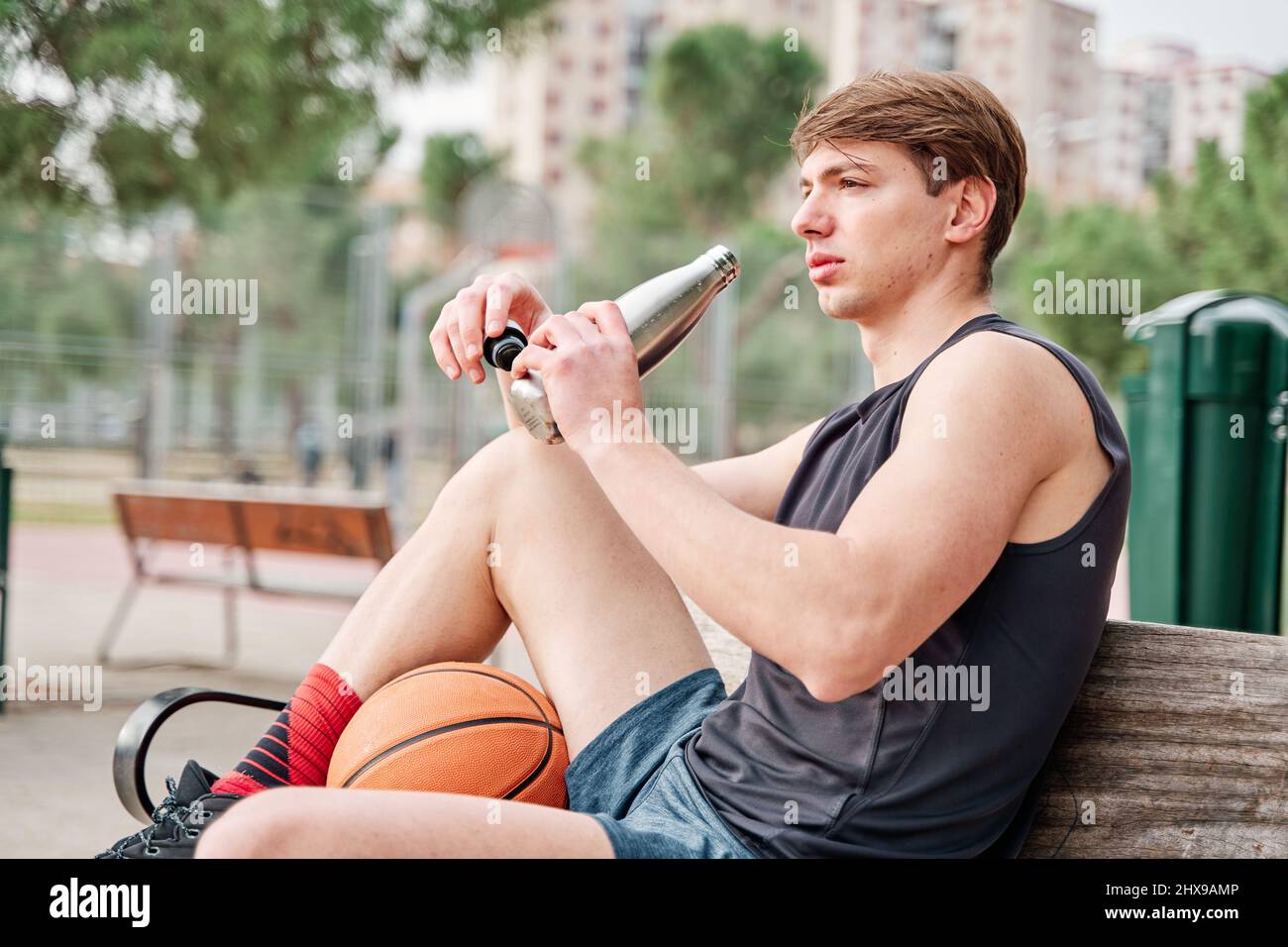 basketball player resting. sportsman sitting holding a bottle of water ...