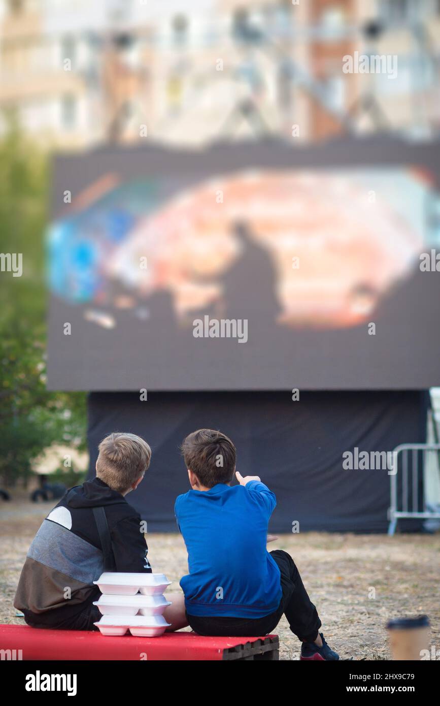 Open-air cinema. Children watching a movie on the screen of a summer ...