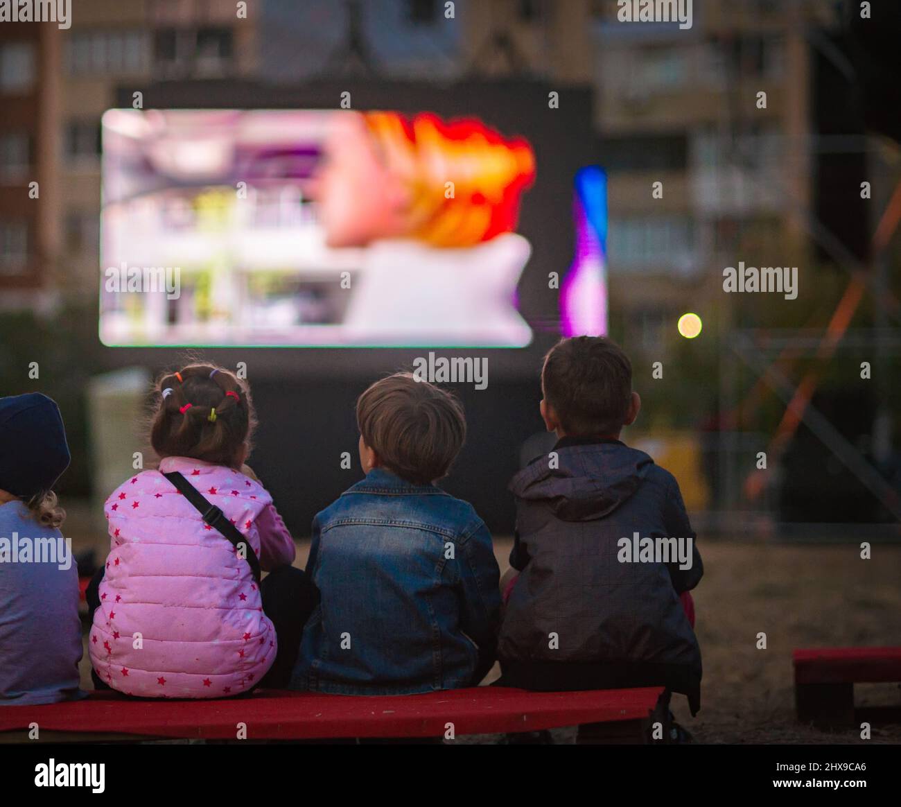 Open-air cinema. Children watching a movie on the screen of a summer ...
