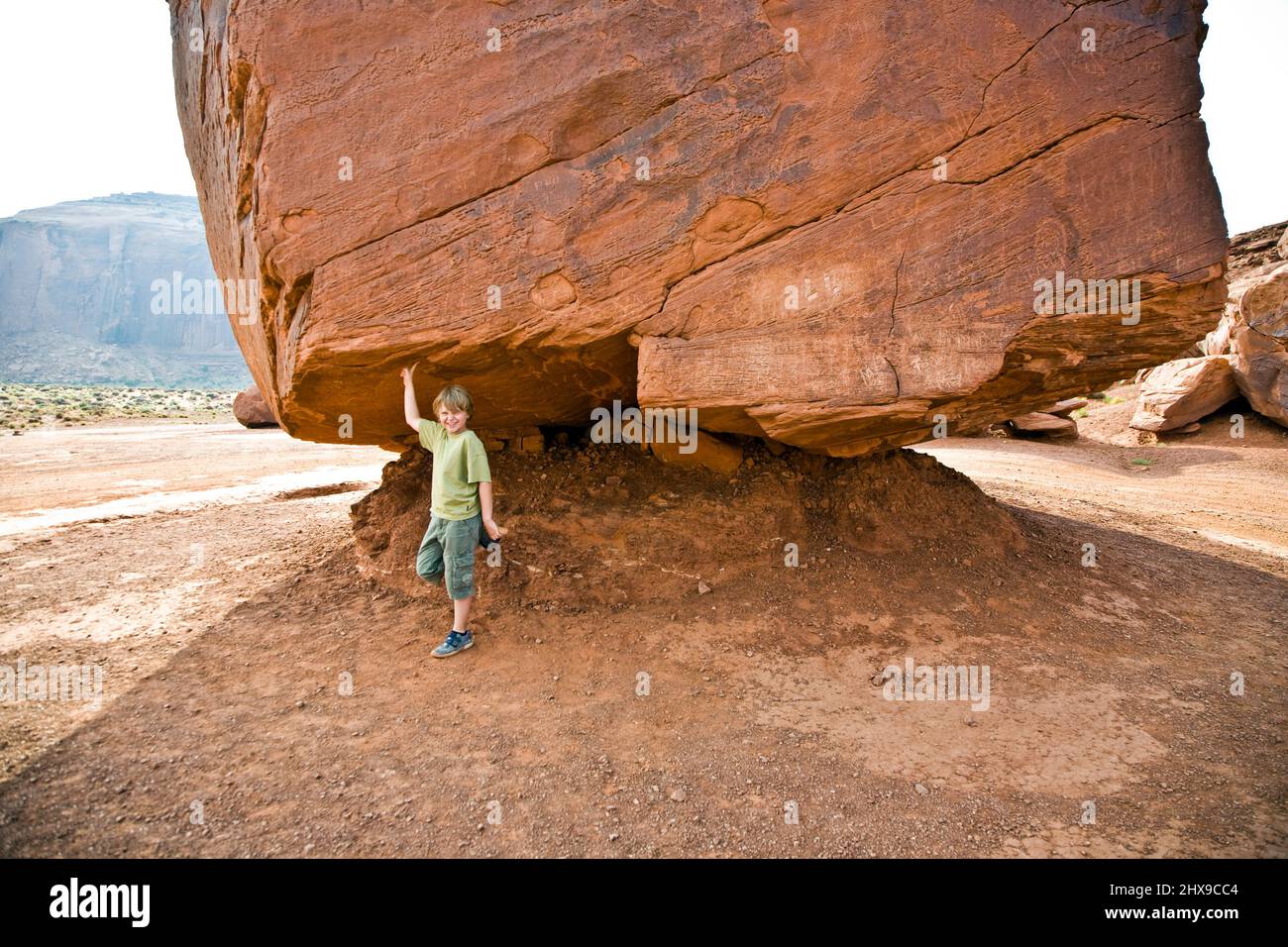 Monument Valley, child has fun by simulatings to carry a big rock with ...