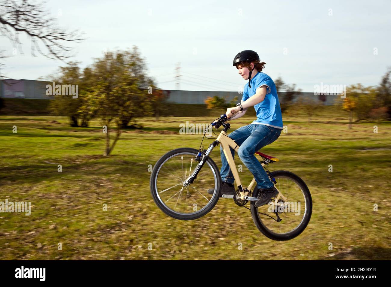 boy jumps with his dirt bike over natural ramps in open area and enjoys ...