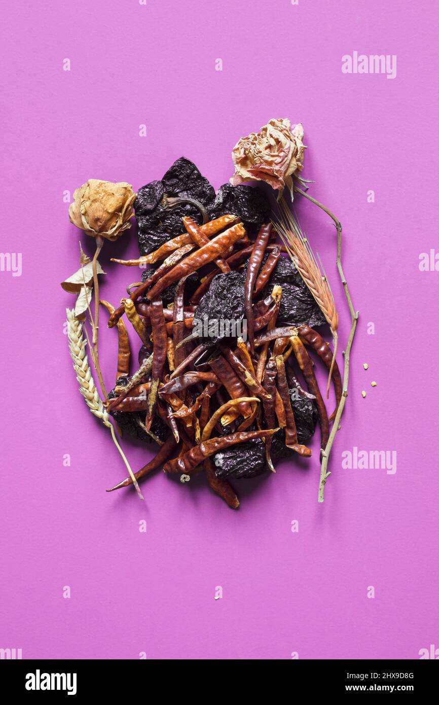 Dried roses surround a cluster of dried chili and jalapeno peppers on a ...