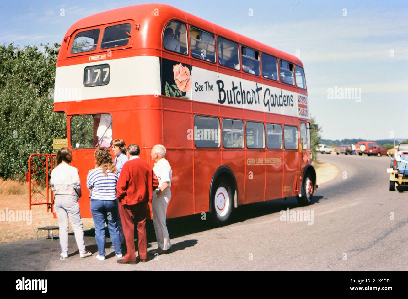 People stand outside a double decker sightseeing bus with a Butchart ...