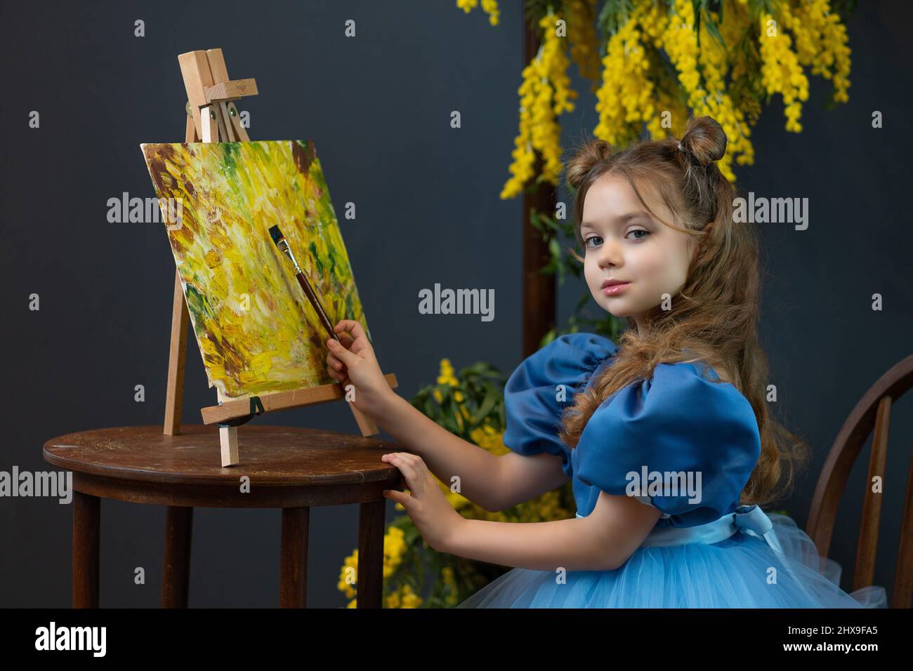 A girl sits near a mimosa and paints a picture in a blue dress mimosa ...