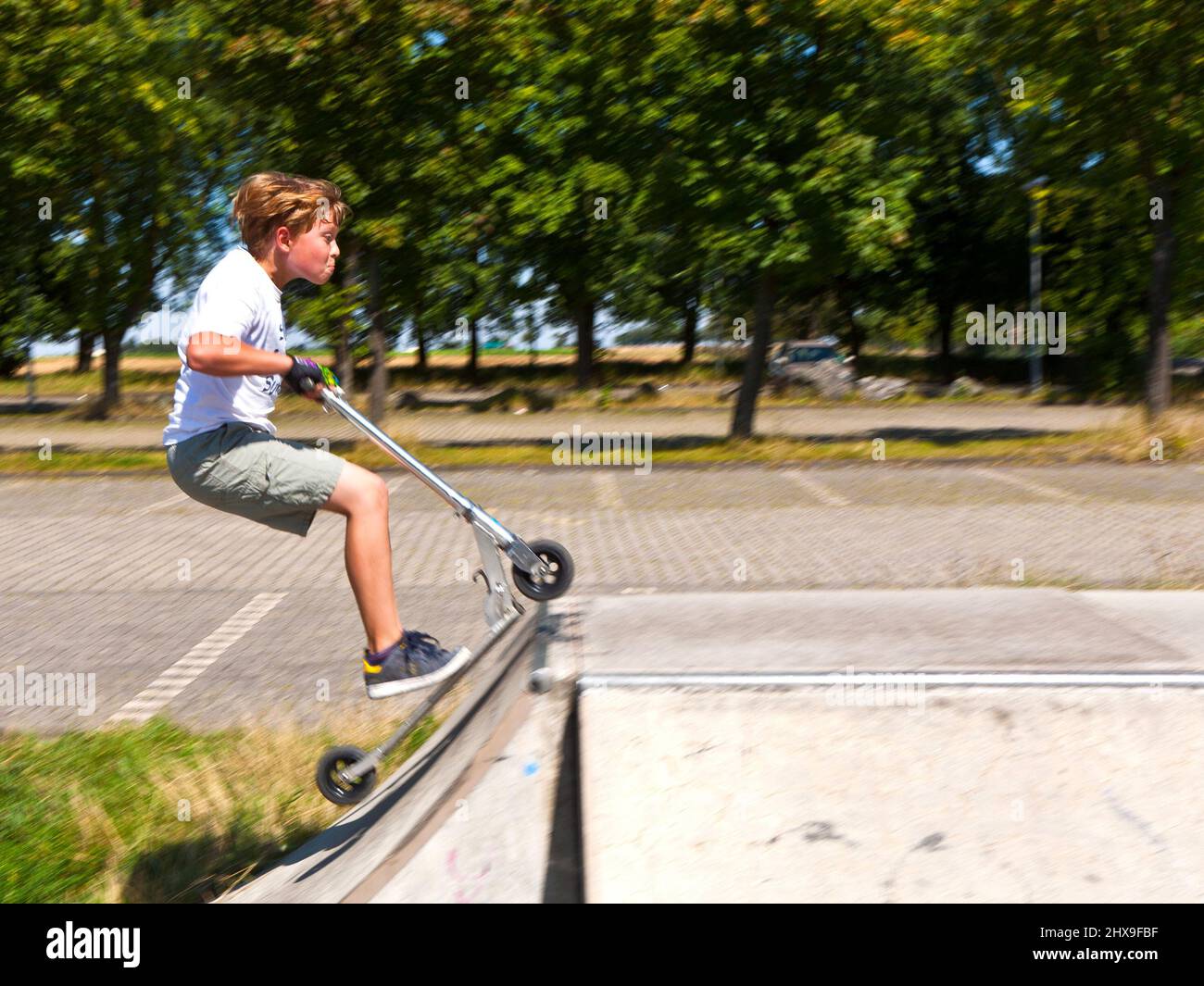 boy has fun at the skate park with his scooter Stock Photo - Alamy