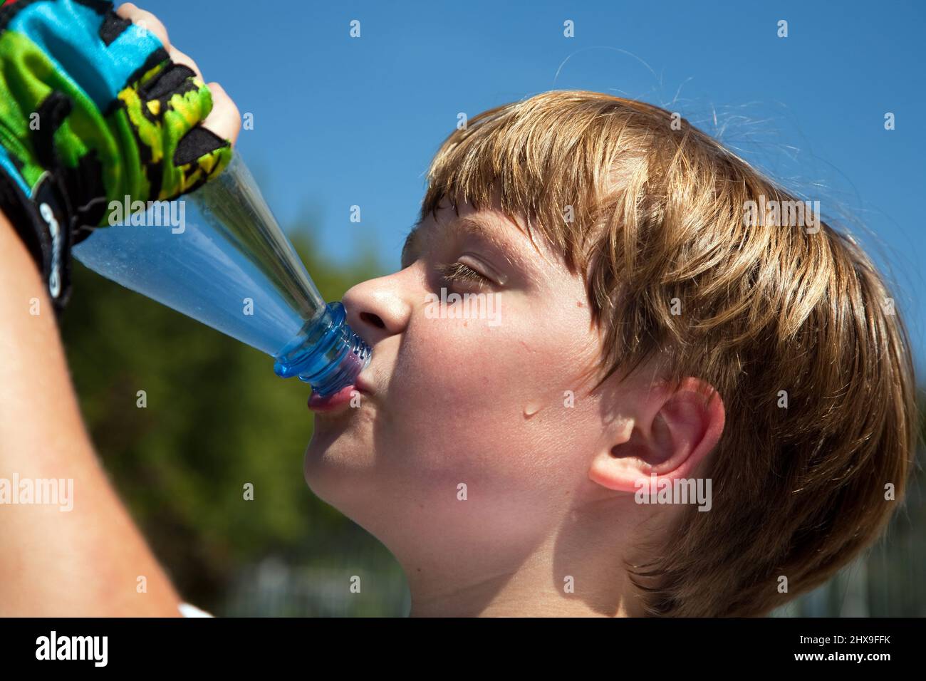 boy is sweating and thursty from doing sports and drinks mineral water ...