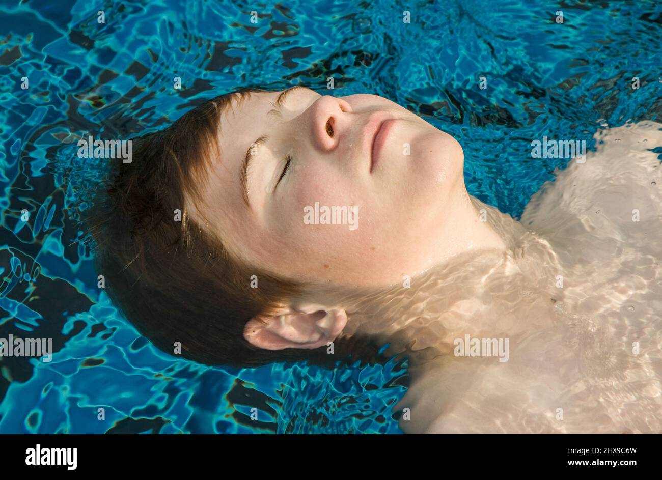 boy enjoys floating on his back in the pool Stock Photo - Alamy