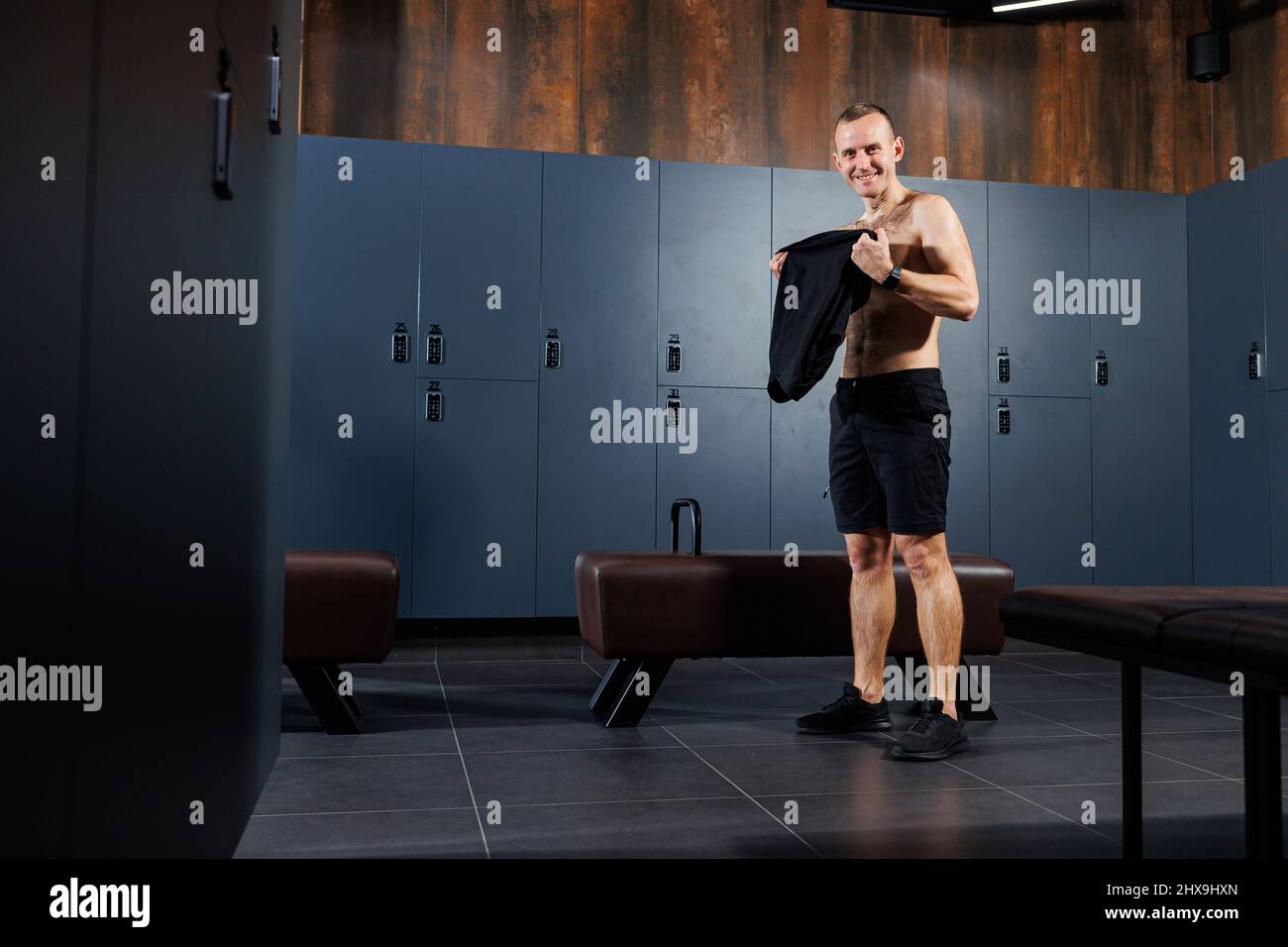 A young man changes clothes in a room in the gym before training Stock ...