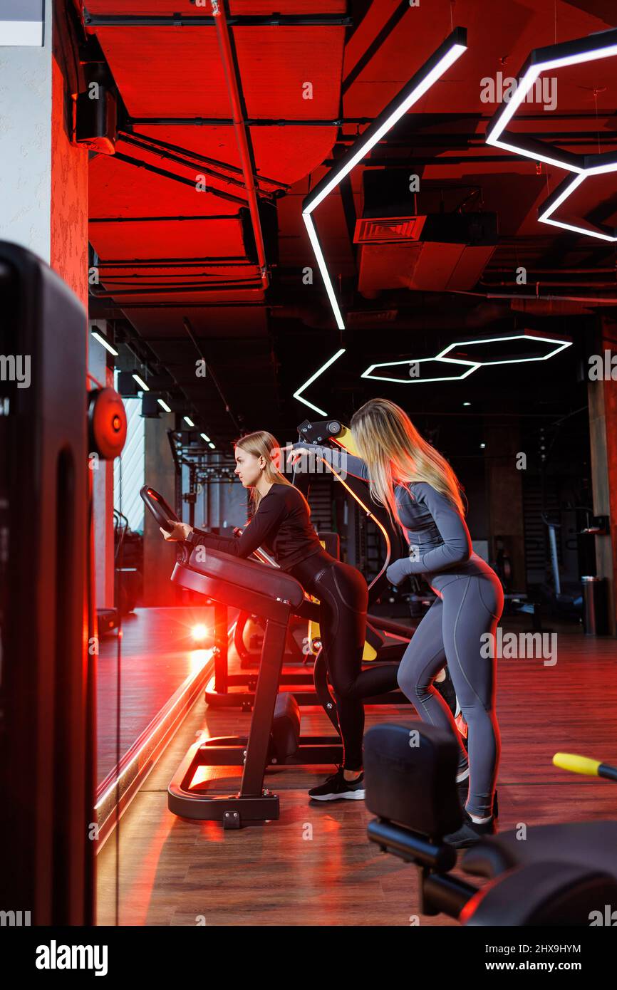 Young slender woman in the gym performs exercises under the guidance of ...