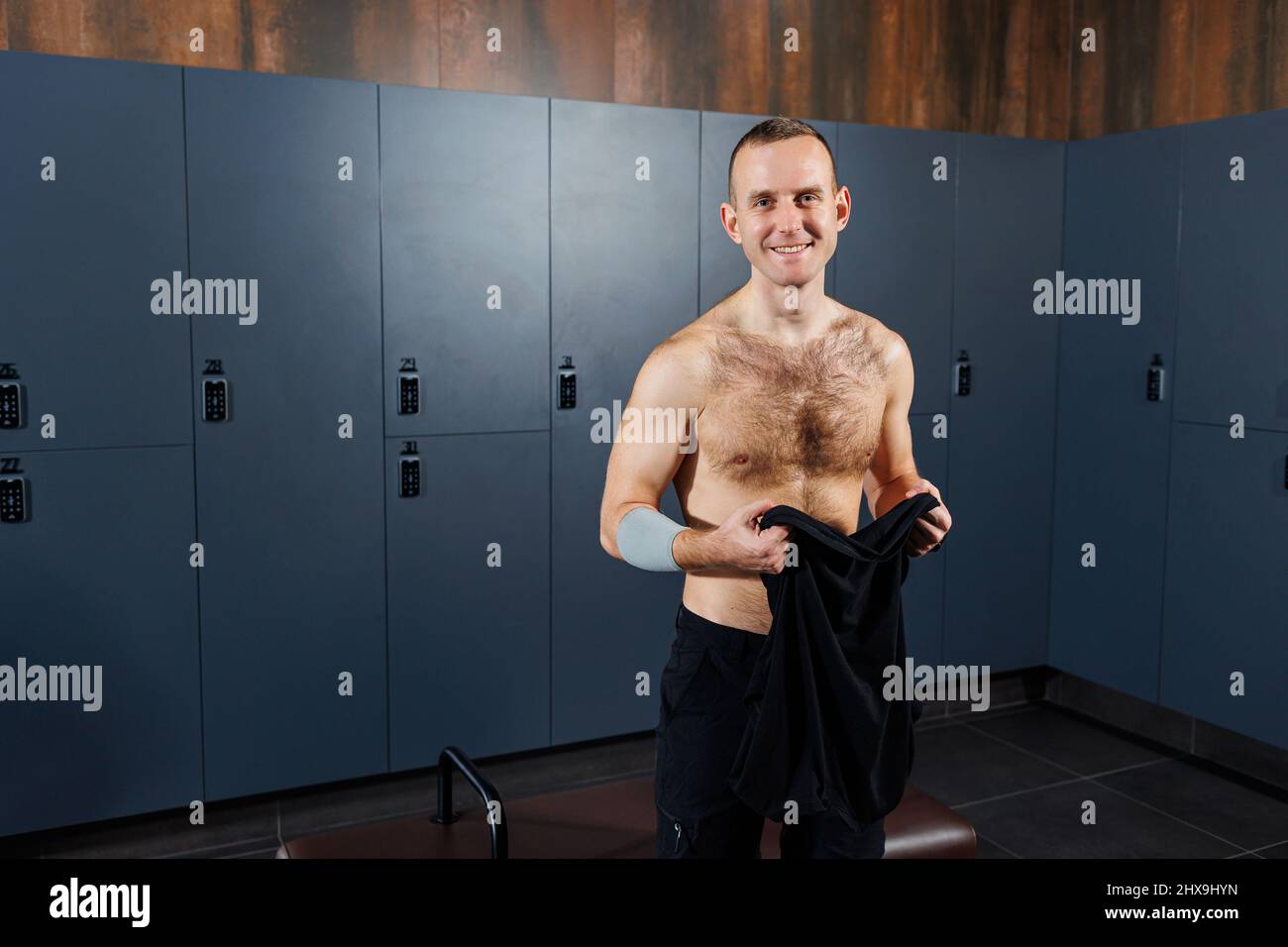 A young man changes clothes in a room in the gym before training Stock ...