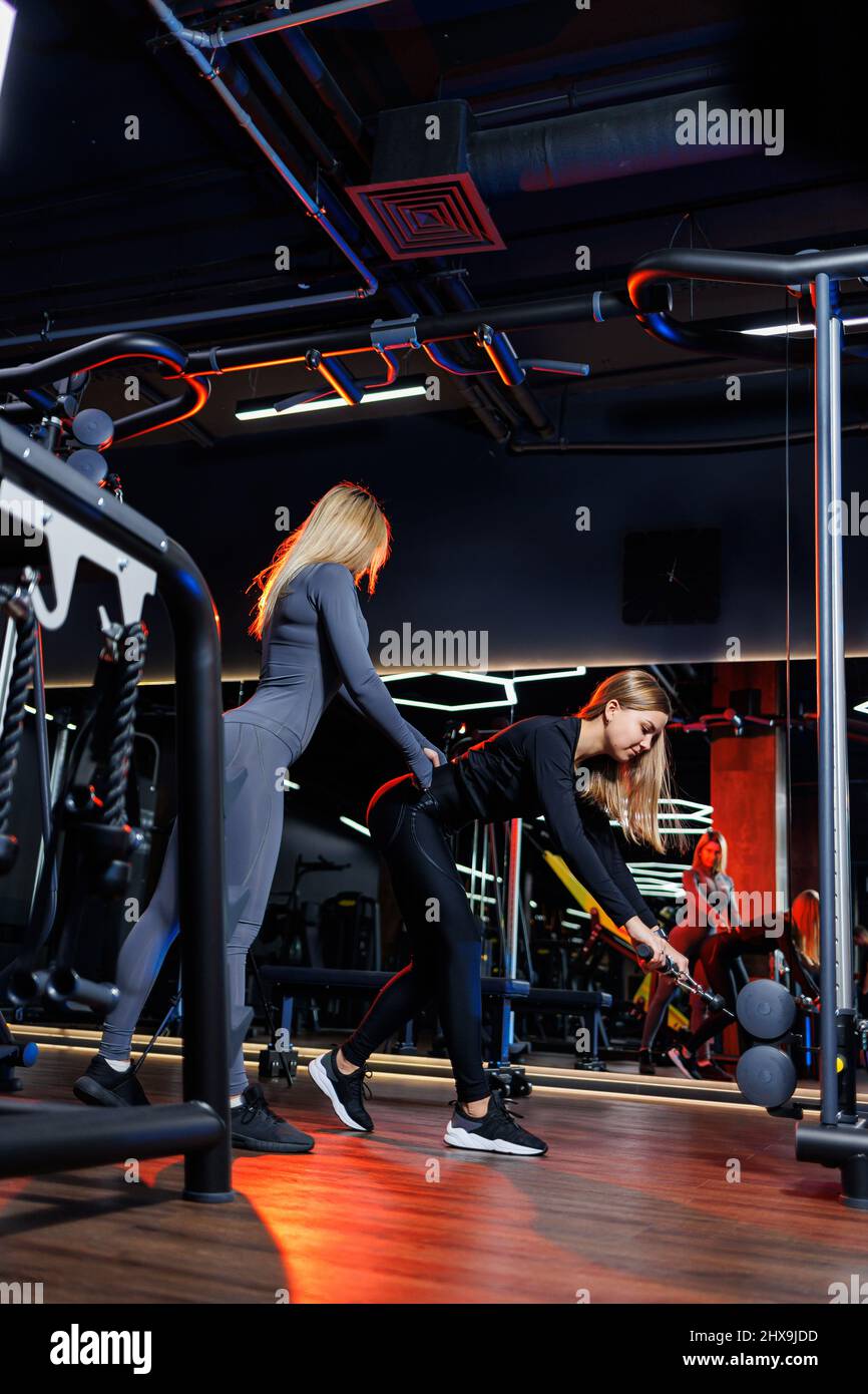 A personal trainer monitors an athletic woman during her workout. Focus ...