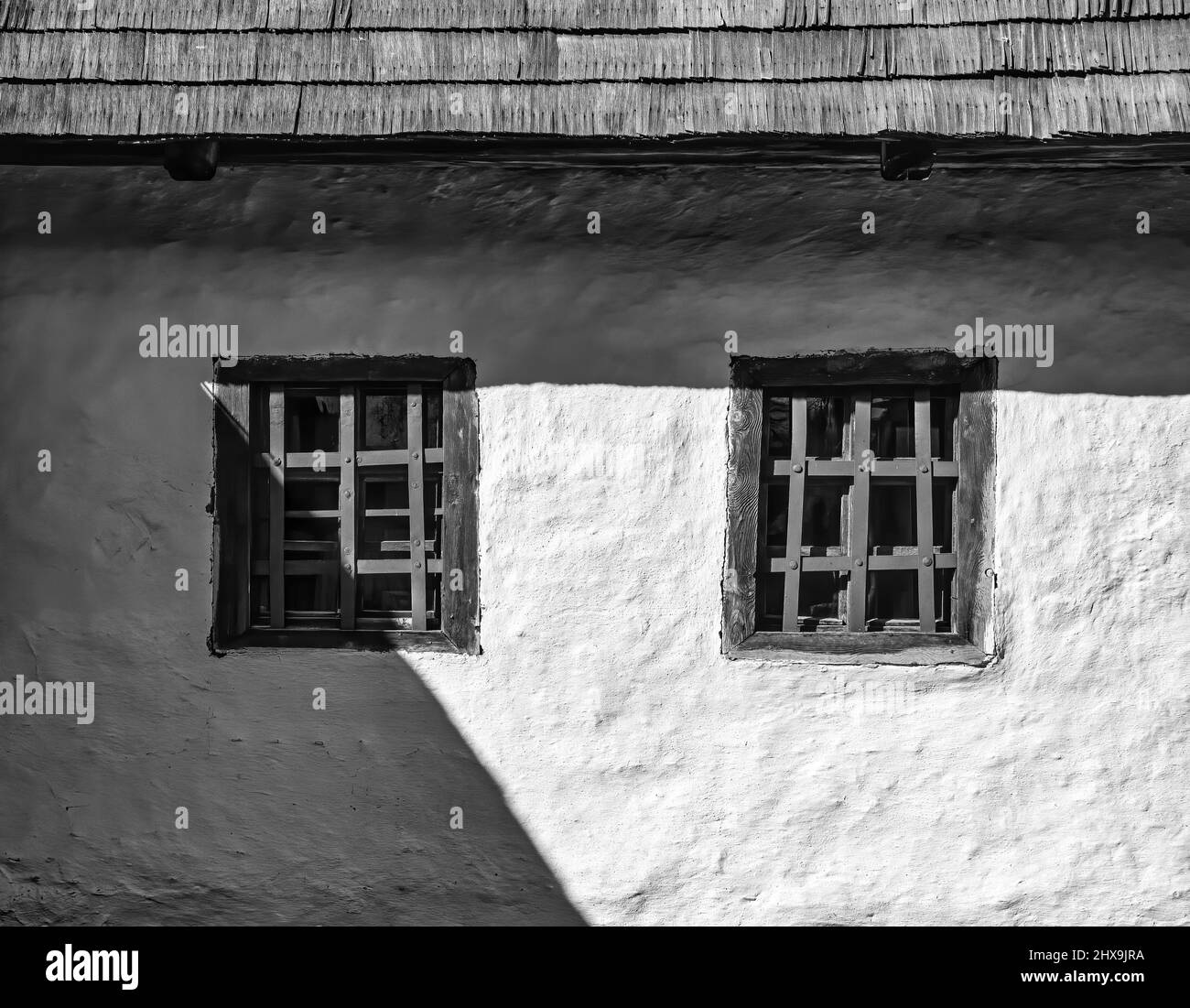 Detail with a white painted old rustic romanian house. Two metal barred ...