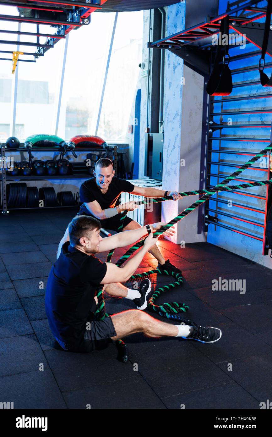 Athletic man doing exercises with the help of his personal trainer in a ...
