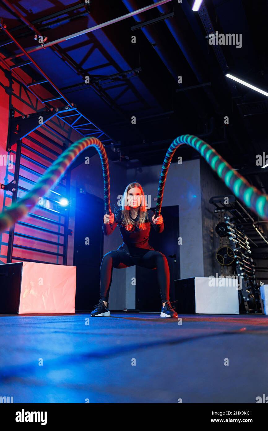 A sportive woman does exercises using sports equipment - rope, goes in ...