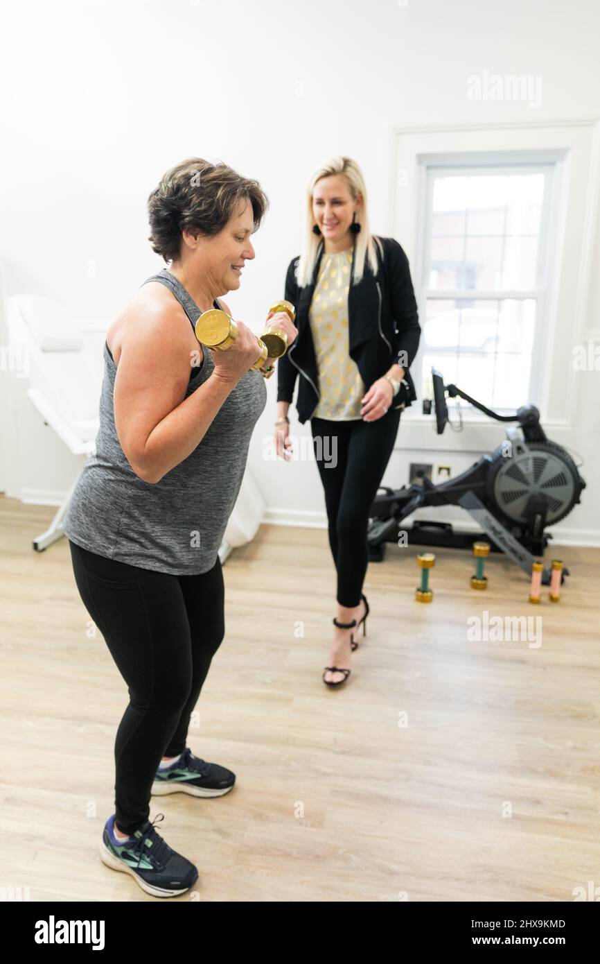 A female personal trainer helping a client exercise, train, and build ...