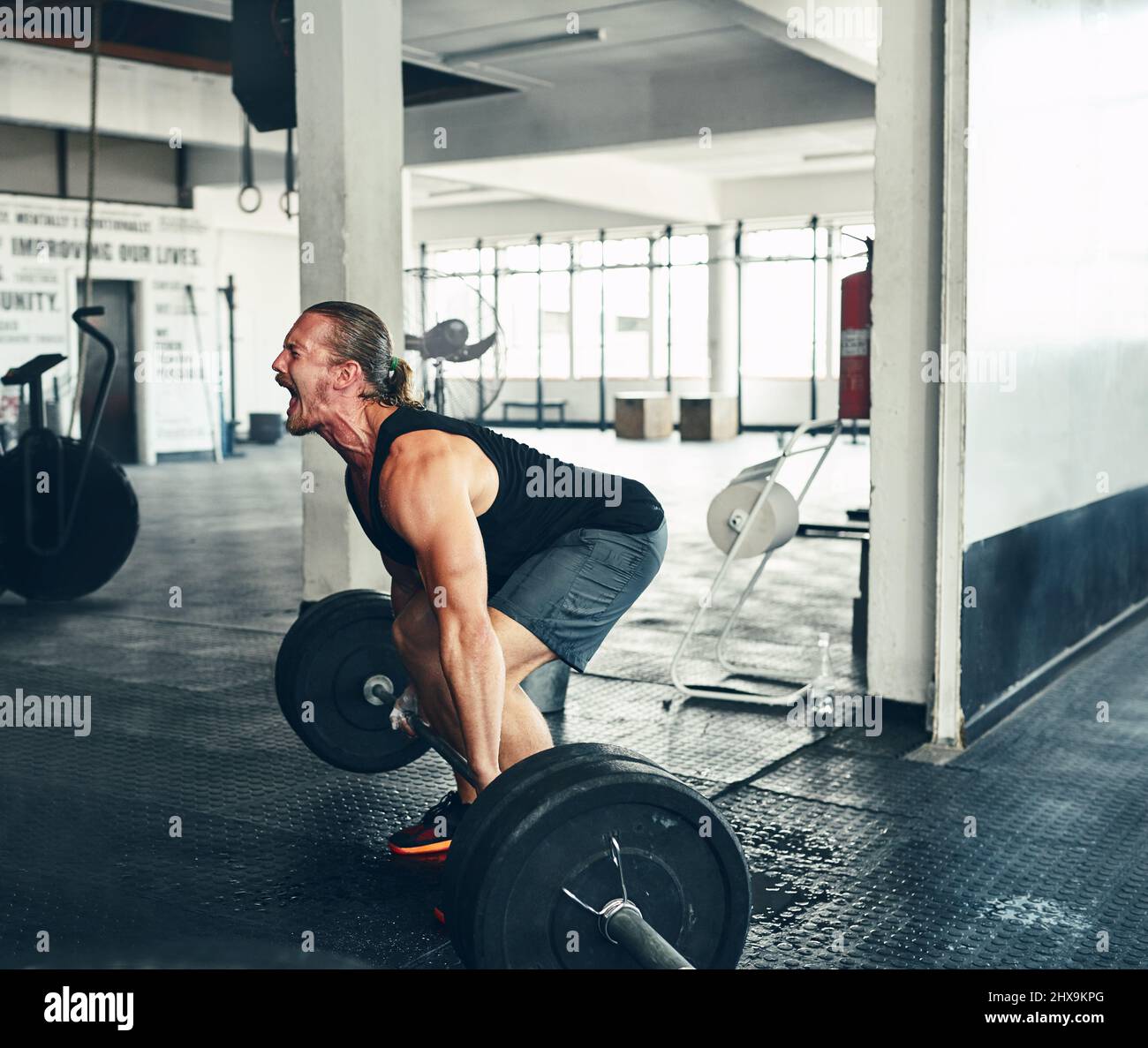 Sore. The most satisfying pain. Shot of a man lifting weights at the ...