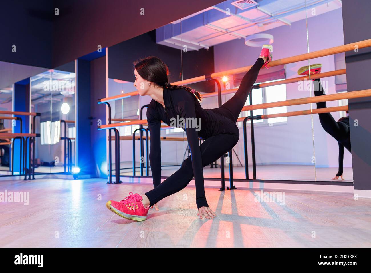 A sportive young woman standing with a raised leg on the railing she is ...