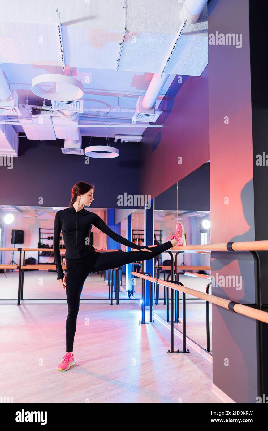 A sportive young woman standing with a raised leg on the railing she is ...