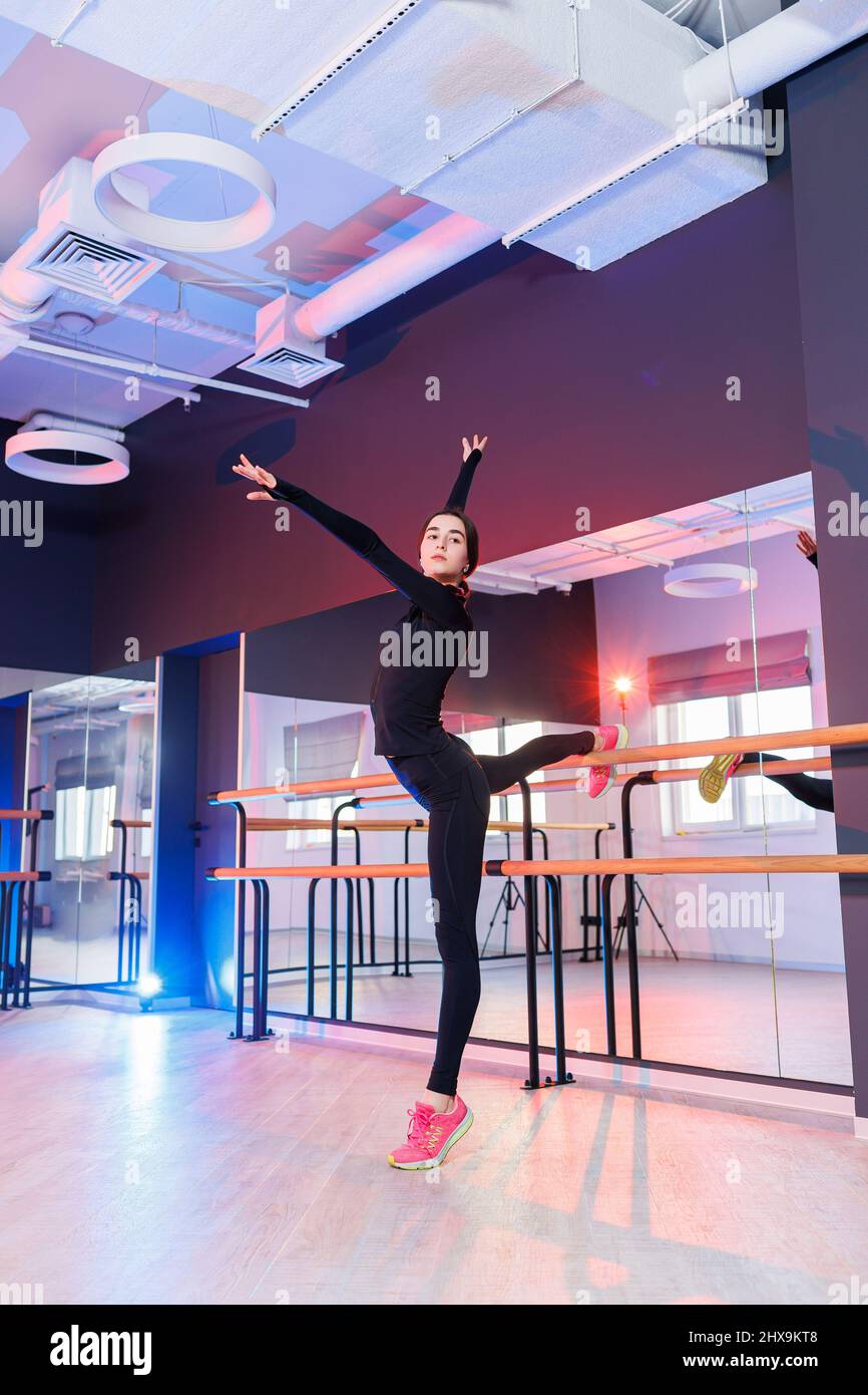 A sportive young woman standing with a raised leg on the railing she is ...