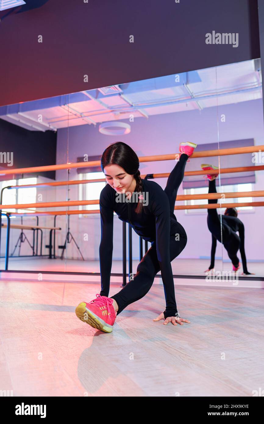 A sportive young woman standing with a raised leg on the railing she is ...