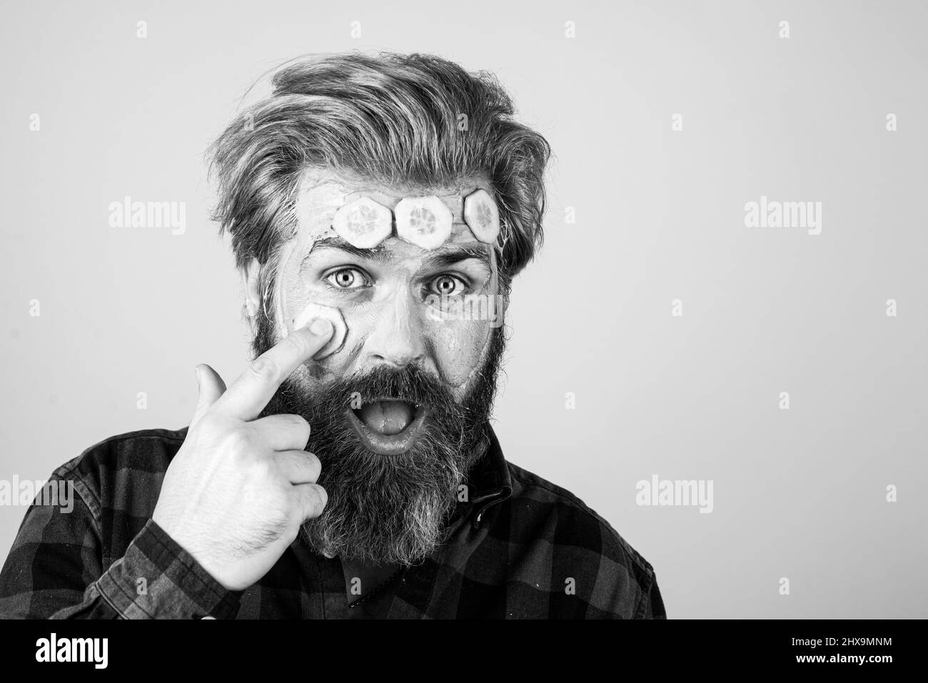 Funny male model with clay mask and cucumber slices on face. Spa ...