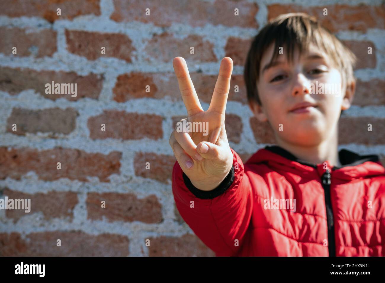 Child Making Peace Sign with Brickwall in Background Stock Photo - Alamy