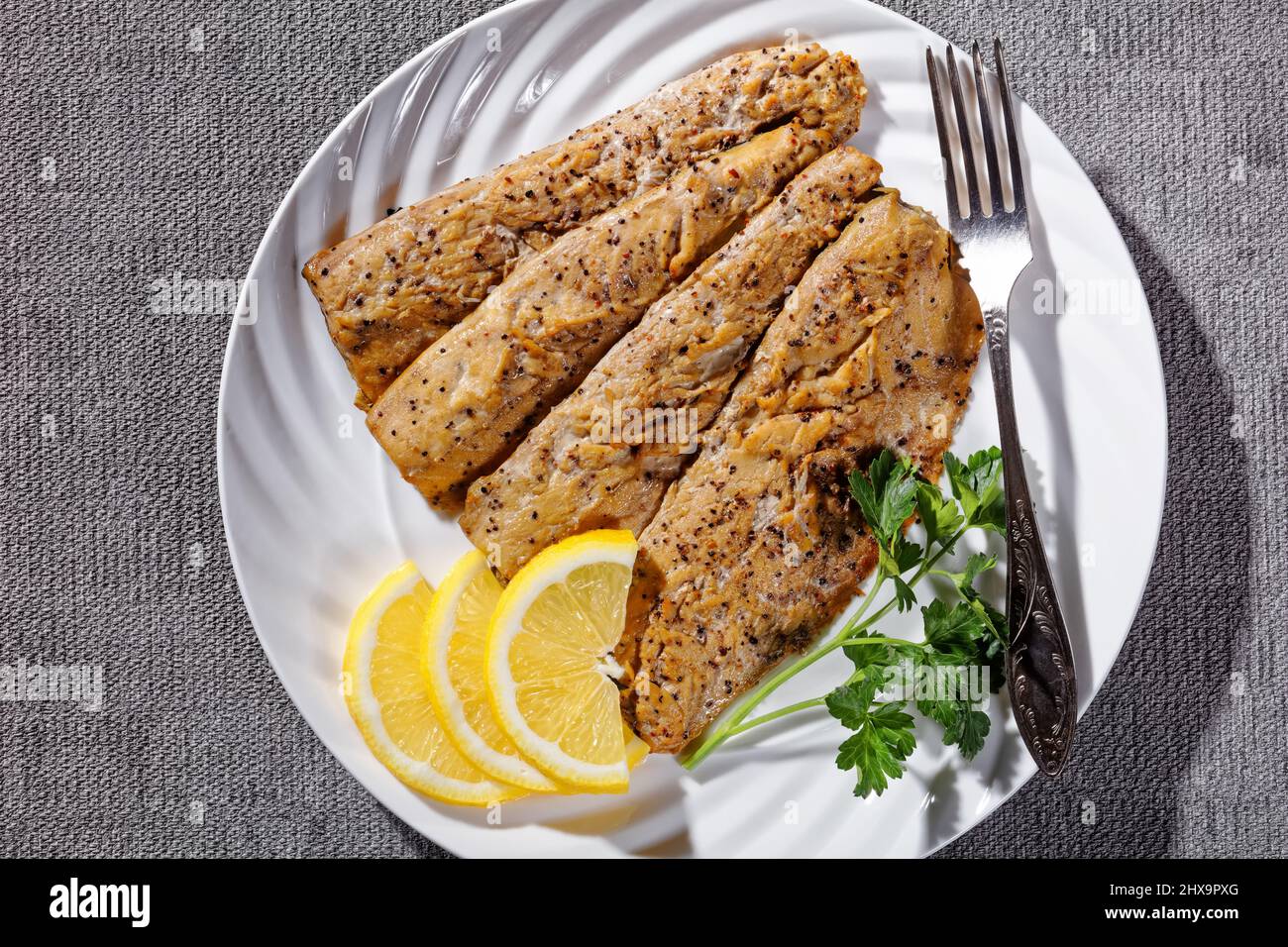 hot smoked spicy scomber, mackerel fish fillets on a white plate with ...