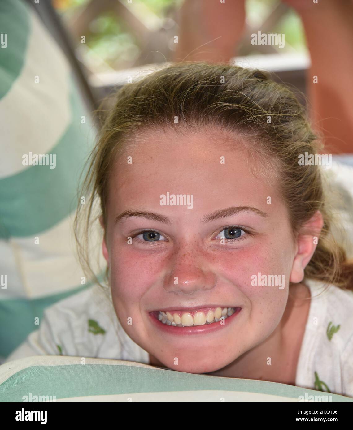 Little girl lays across green striped pillows and smiles her biggest ...