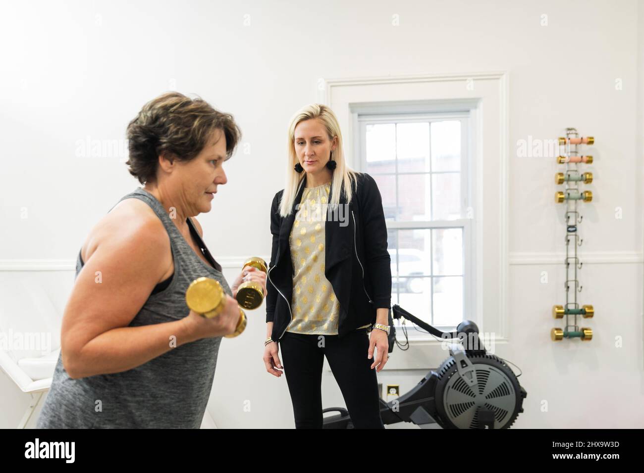 A female personal trainer helping a client exercise, train, and build ...
