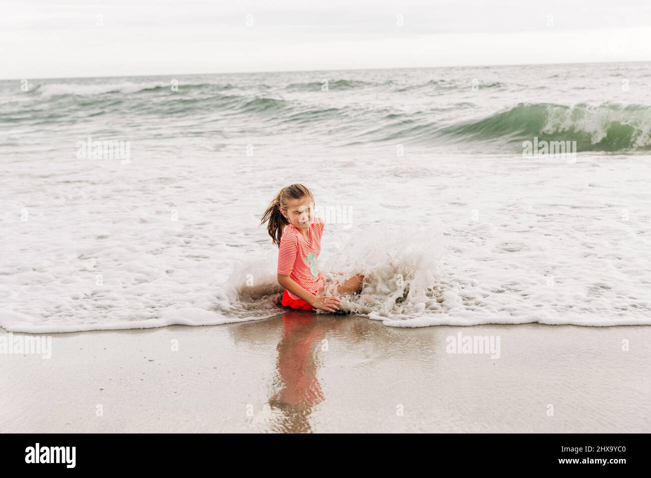 Young girl getting hit with a wave while sitting in the ocean Stock ...