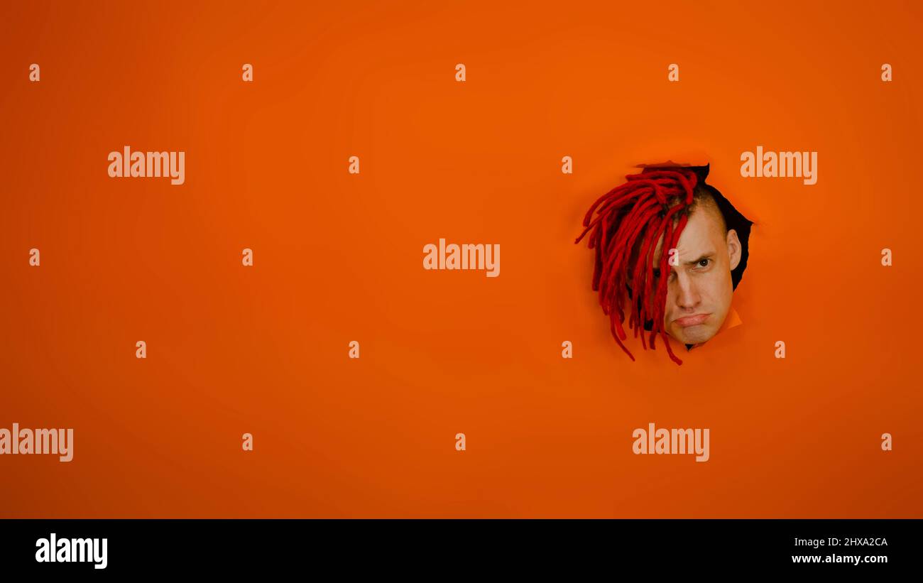 Young man with sad expression on his face sticking out of hole of ...