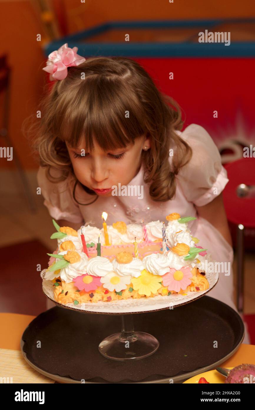 A girl blows out candles on a birthday cake Stock Photo - Alamy