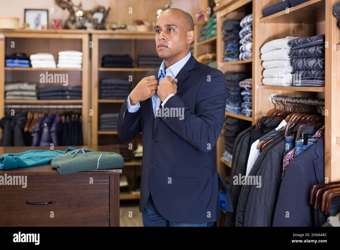 Man choosing suit jacket in clothing store Stock Photo - Alamy