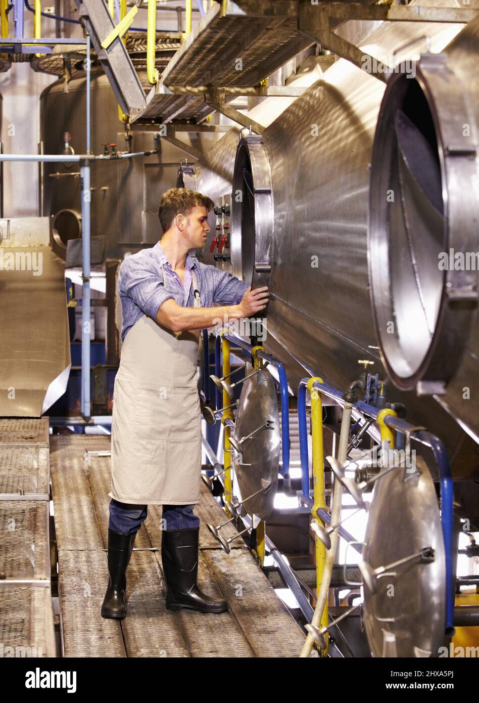 Some routine machine maintenance. A young wine maker checking on his ...