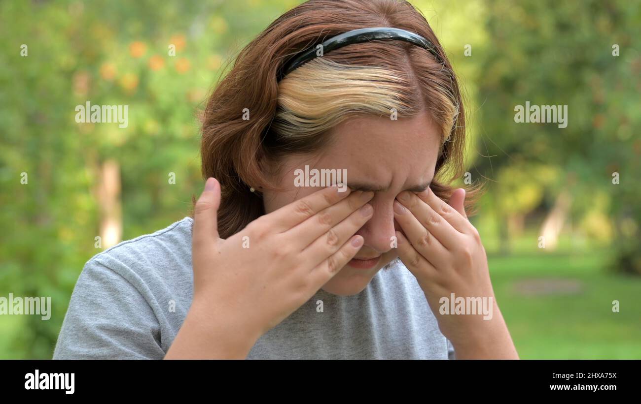 a teenage girl cries with resentment and rubs her eyes with her hands ...