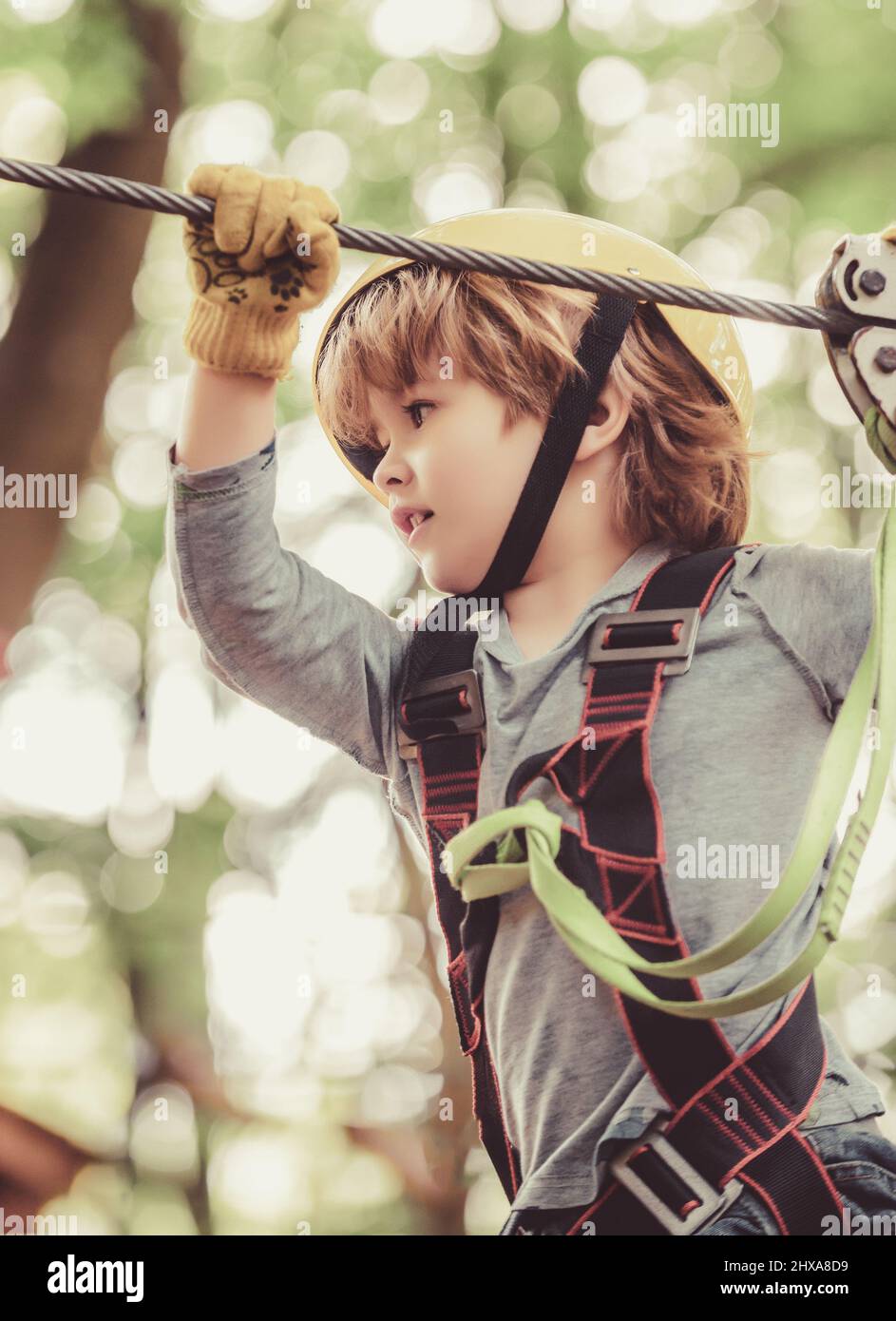 Cute child in climbing safety equipment in a tree house or in a rope ...