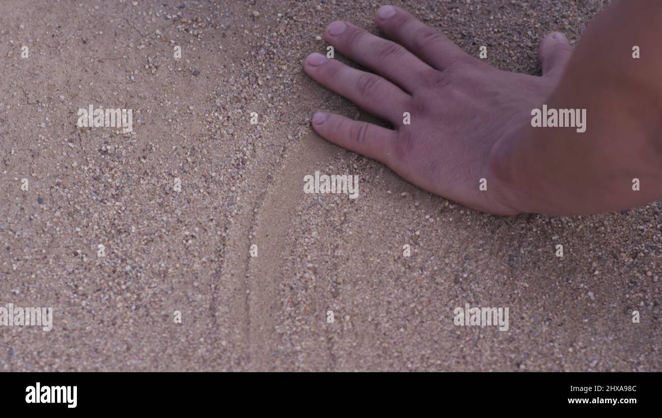 Close up of man's hand touching sand at the shore of the sea - concept ...