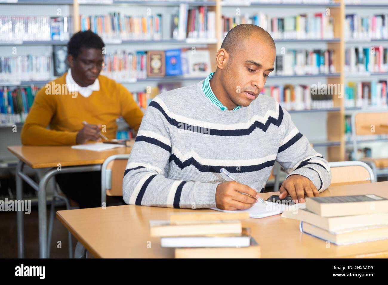 Young adult man studying in public library Stock Photo - Alamy