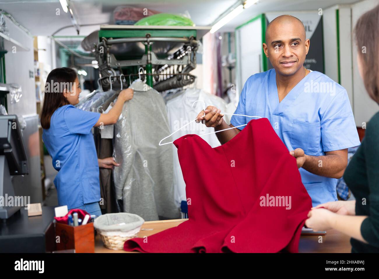 Man dry-cleaning worker giving clothes to customer Stock Photo - Alamy