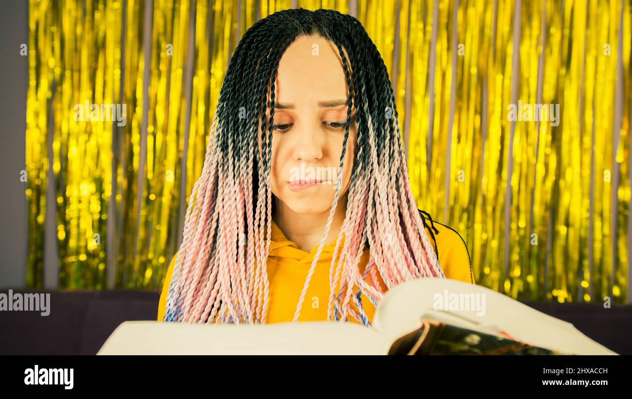 Young woman with multicolored hairstyle reading book. Pretty female ...