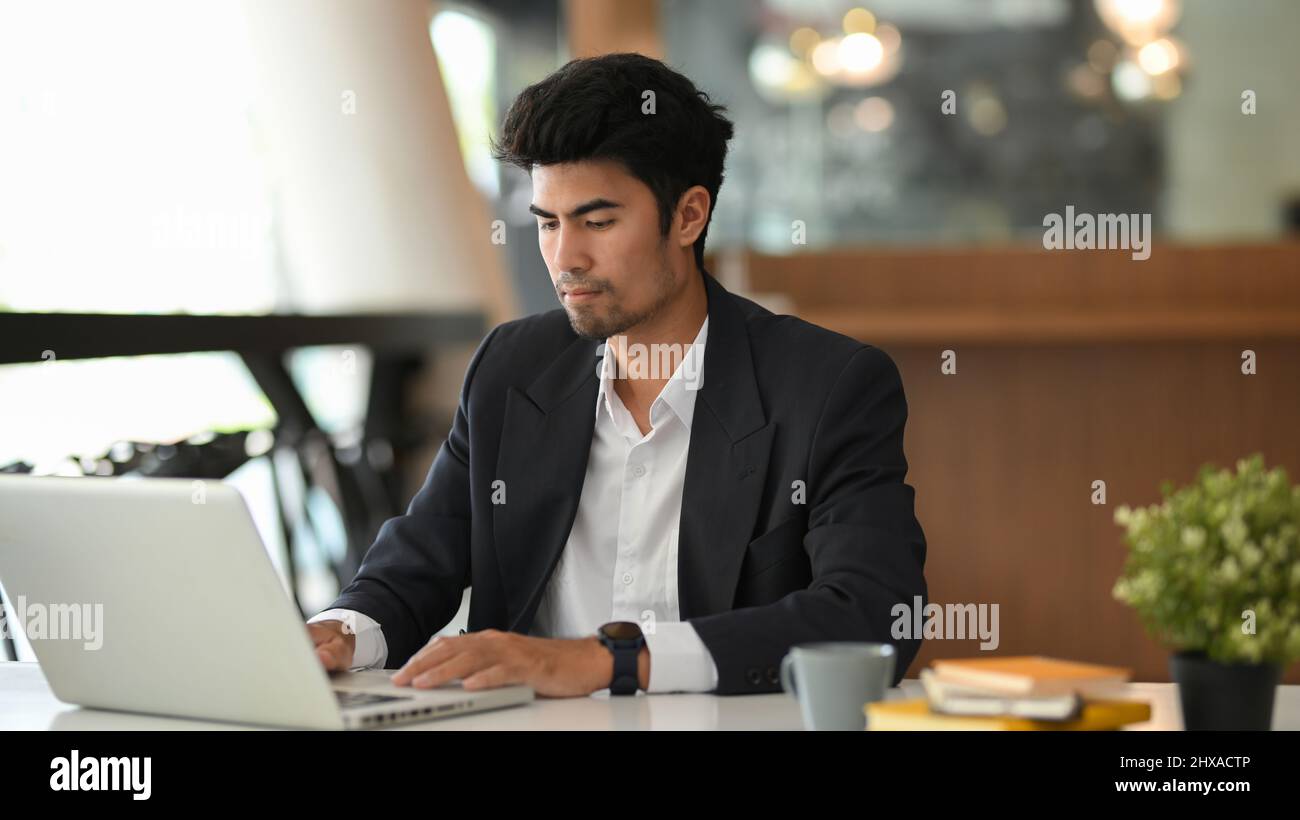 Focused Asian male boss in business suit working on laptop computer in ...