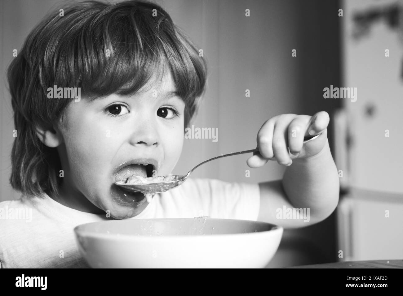 Hungry little boy eating. Cheerful baby child eats food itself with ...