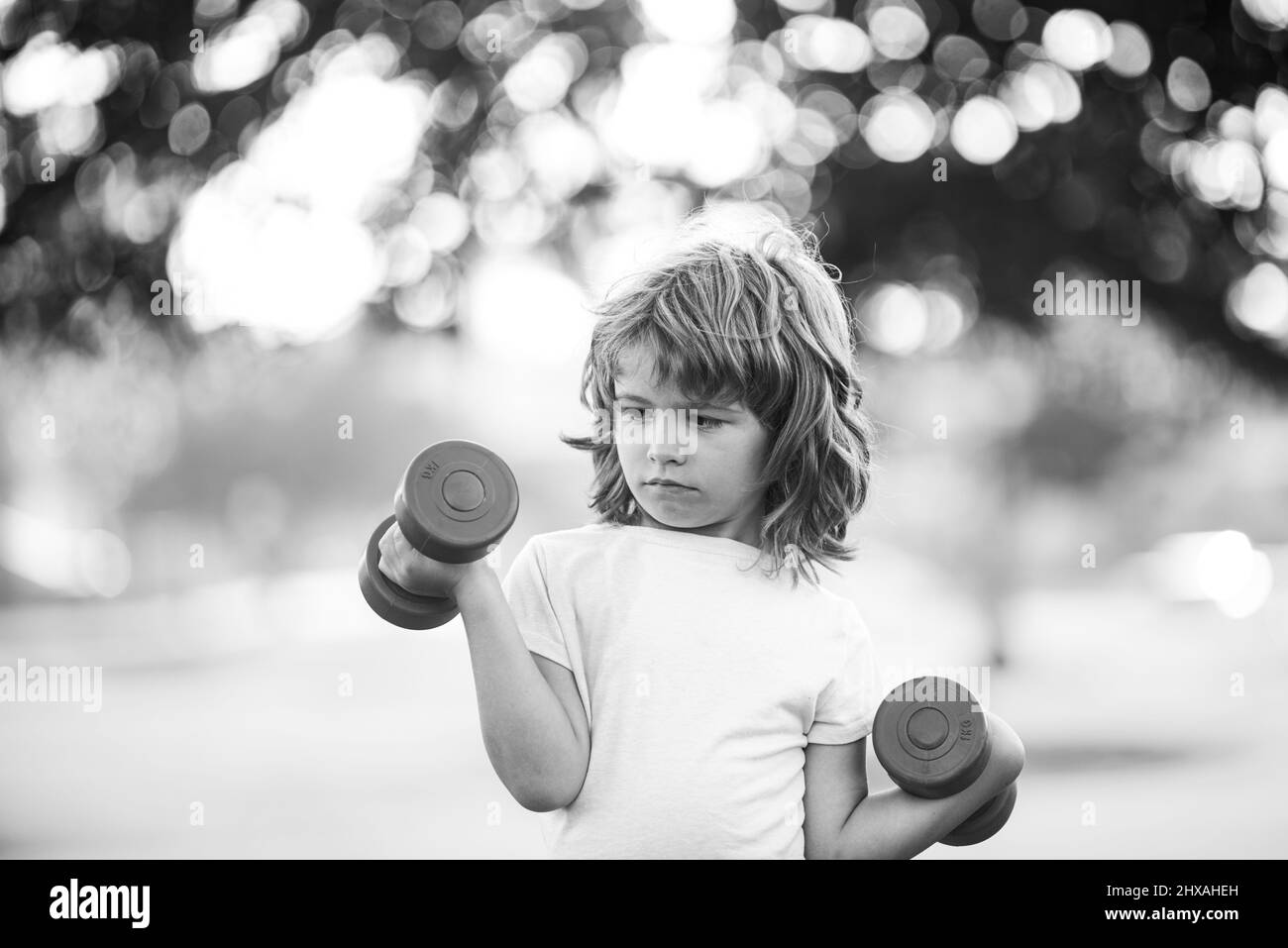 Sporty kid with dumbbell outdoor. Kids sport. Boy exercising in park ...