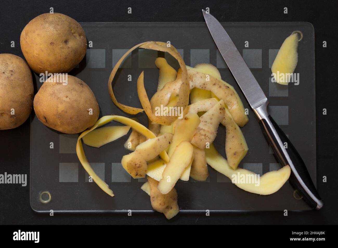 top view of raw unpeeled potato with peels and ordinary life on glass ...